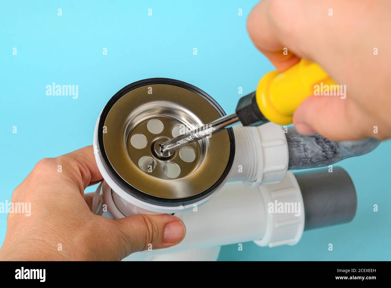 Woman hands unscrew a strainer from new waste water trap on a blue ...