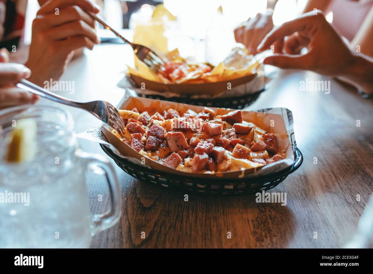 Side view of crop anonymous people sitting at wooden table and eating ...