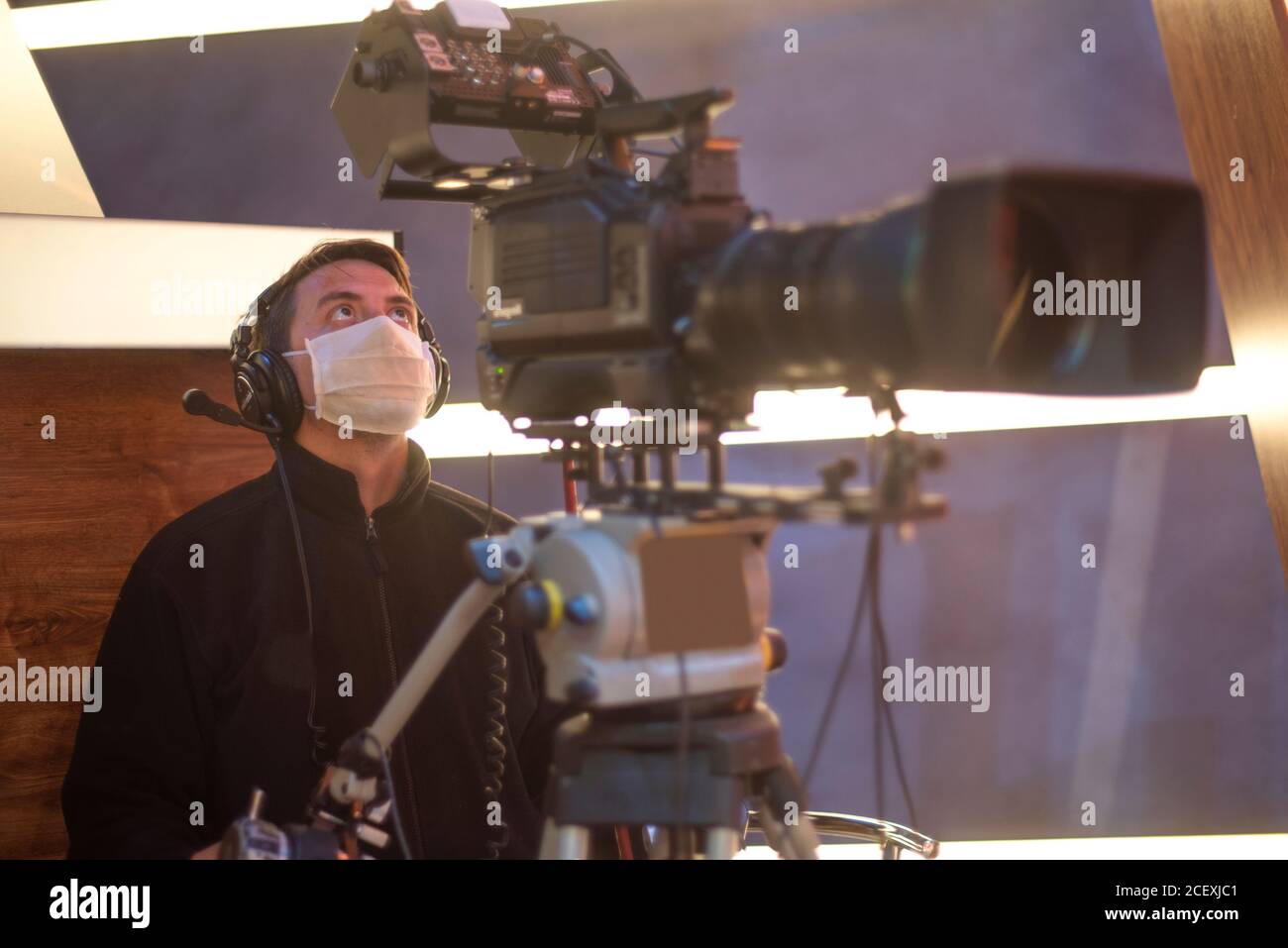 masked cameraman is filming a television show in the studio. TV Stock ...