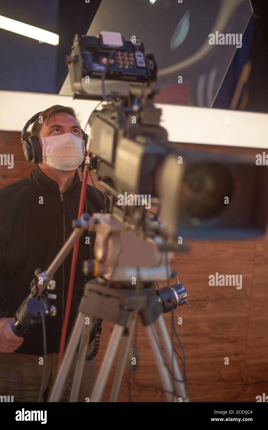 masked cameraman is filming a television show in the studio. TV Stock ...