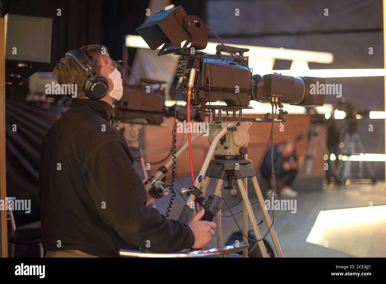 masked cameraman is filming a television show in the studio. TV Stock ...