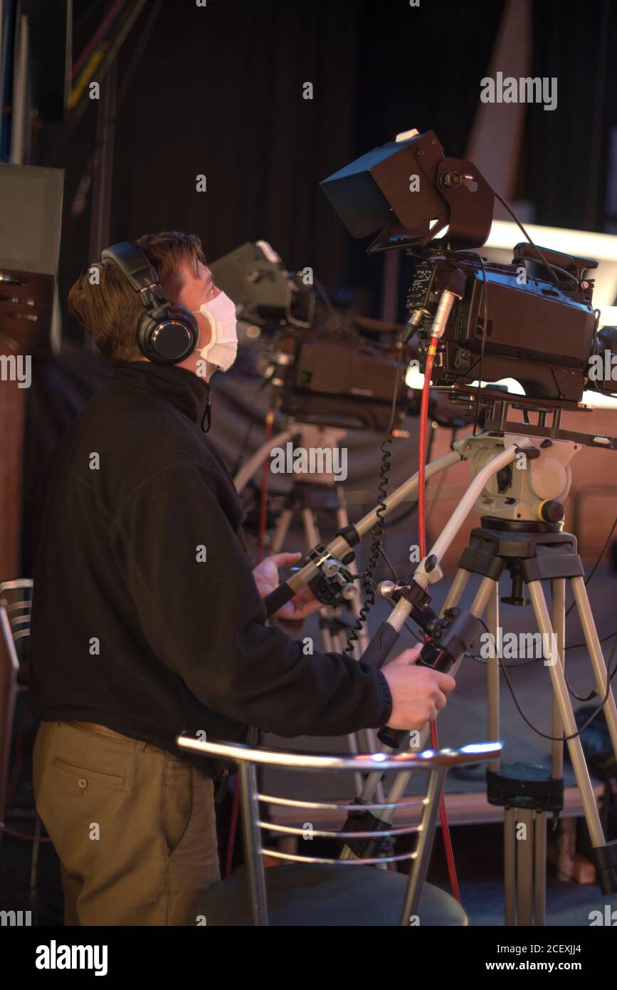 masked cameraman is filming a television show in the studio. TV Stock ...