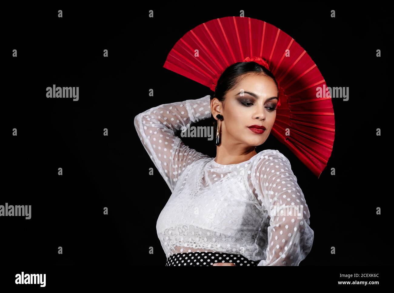Full body young Hispanic female dancer in colorful costume with red fan ...