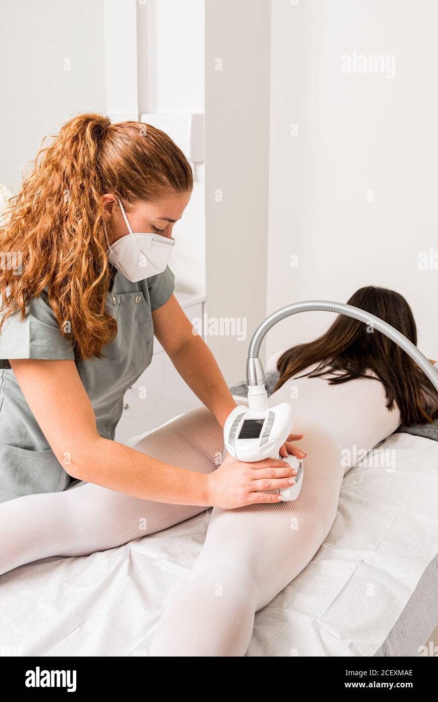 Masseuse in protective mask doing anti cellulite lipo massage to female ...