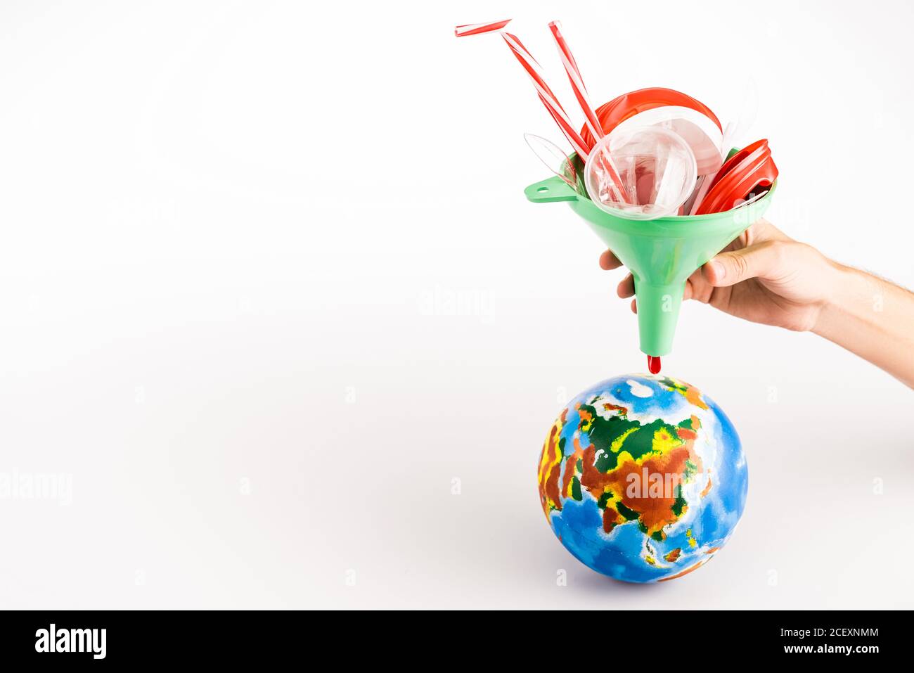 cropped view of man holding funnel with plastic above globe on white ...