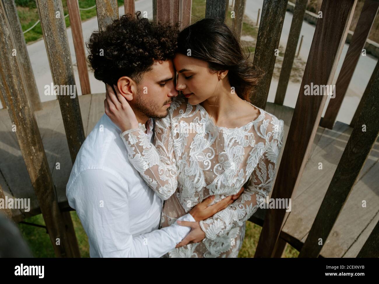 High angle of sensual newlywed couple in stylish clothing cuddling ...