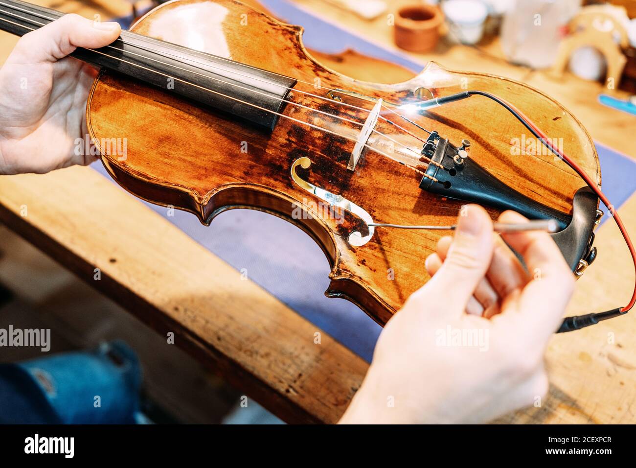 Crop anonymous craftsman setting sound post while building string ...