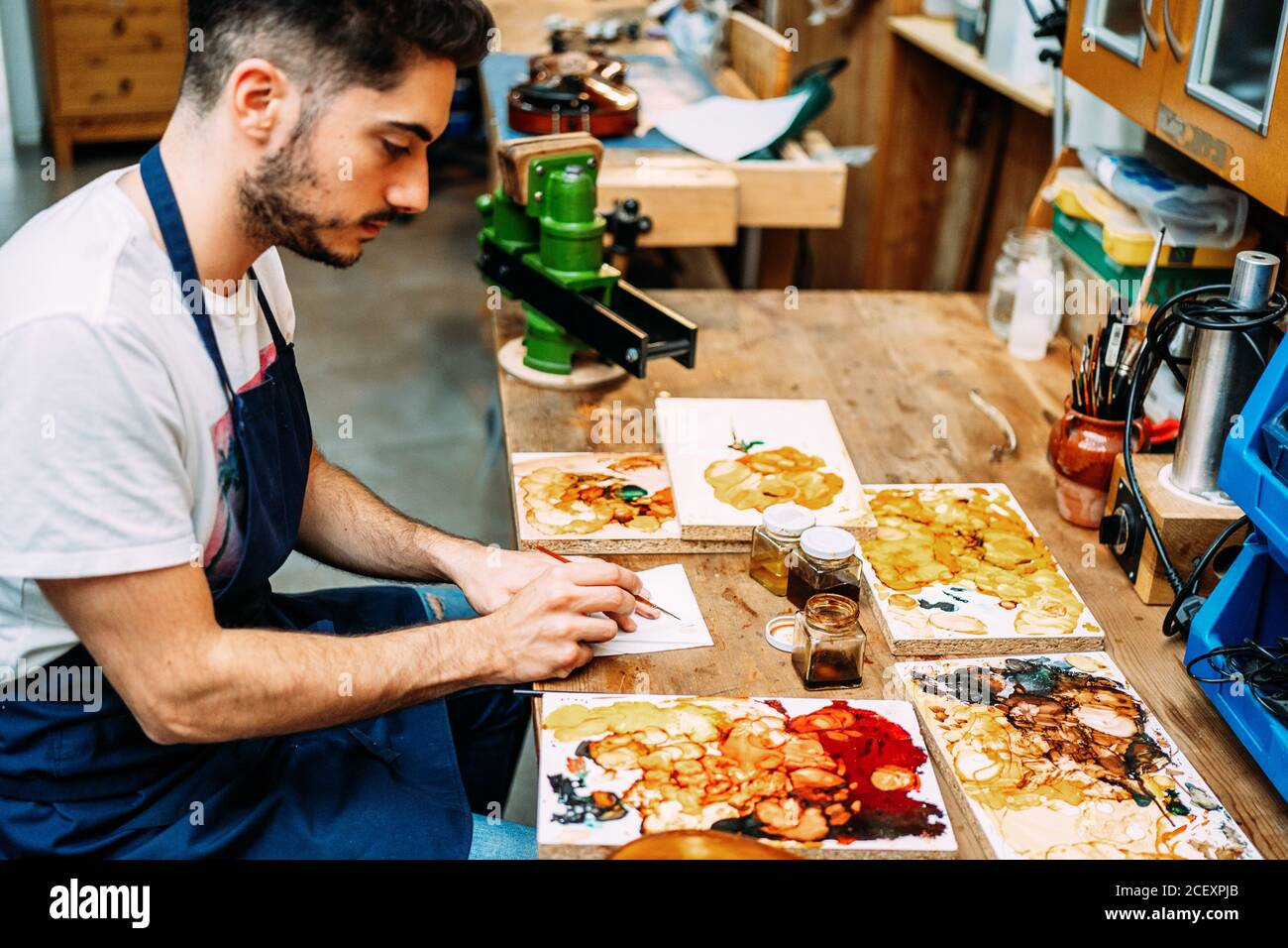 High angle side view of male artisan luthier sitting at counter and ...
