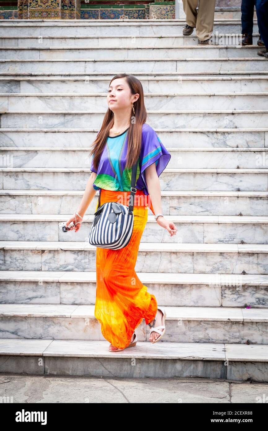 A young Asian tourist happily skips down the steps of one of the ...