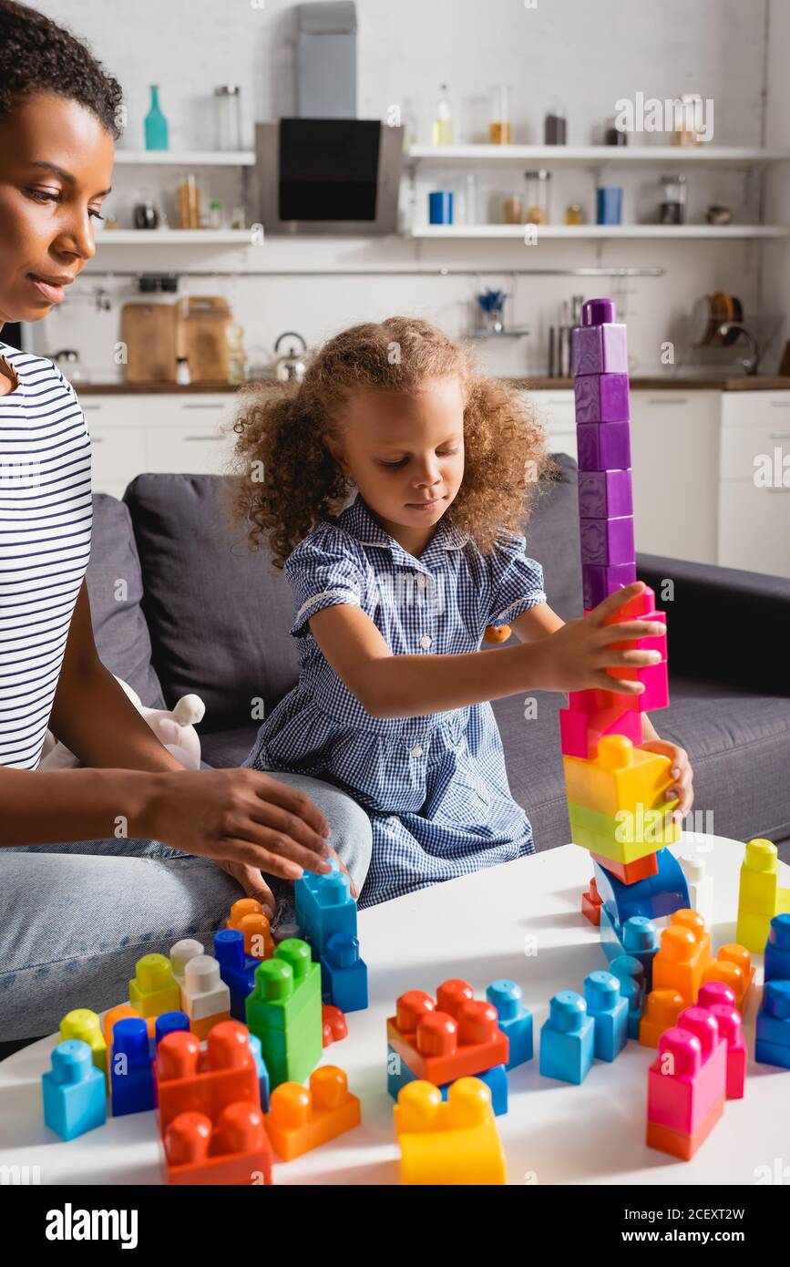 selective focus of african american girl building tower from ...