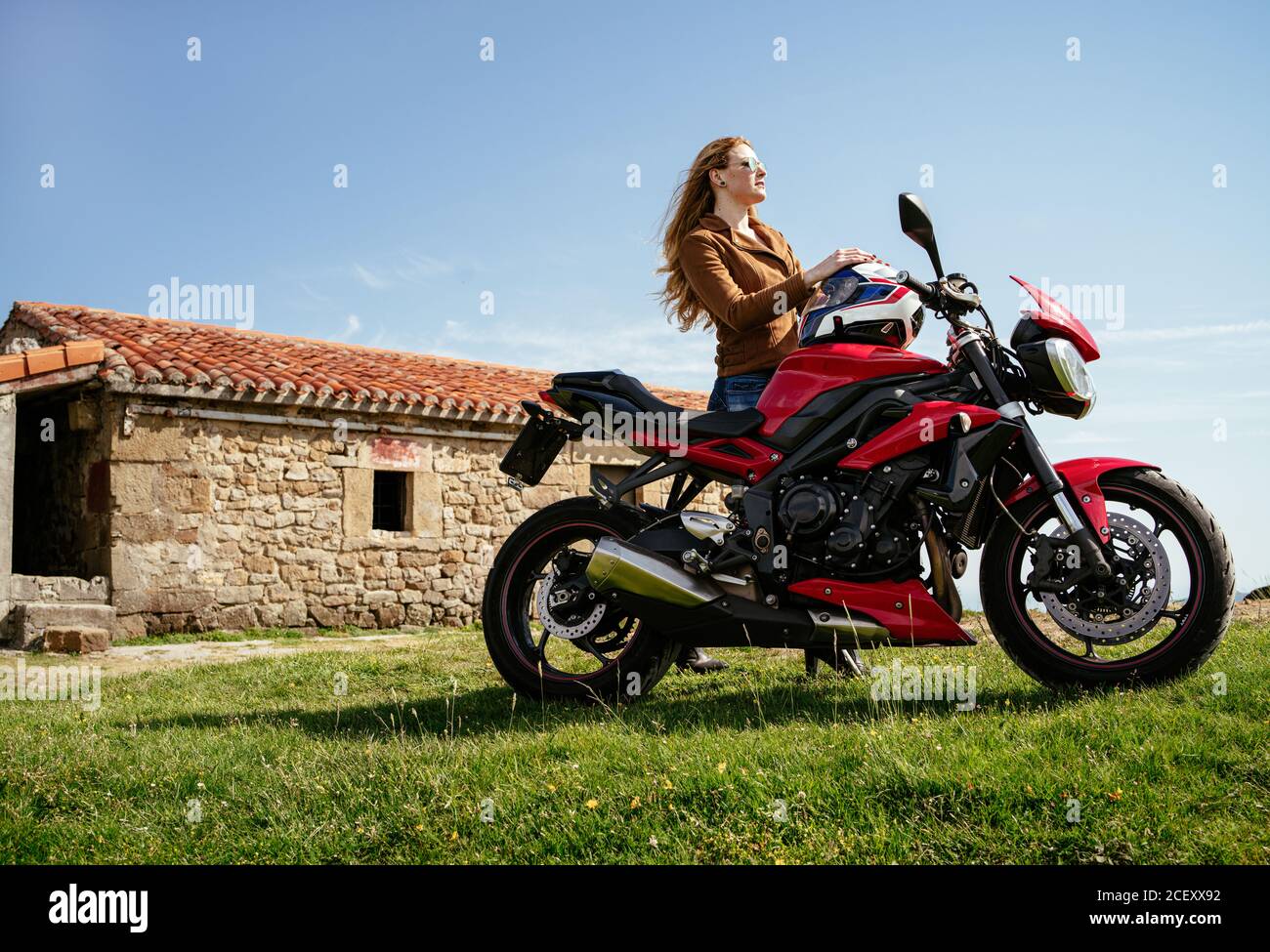 Side view low angle of brutal female biker standing near motorbike in ...