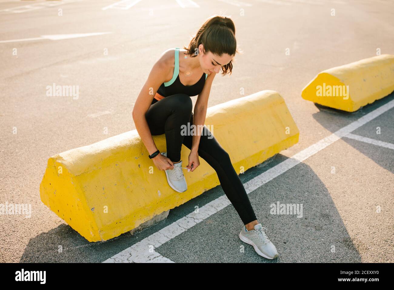 Full body of young slim female runner in black sportswear sitting on ...