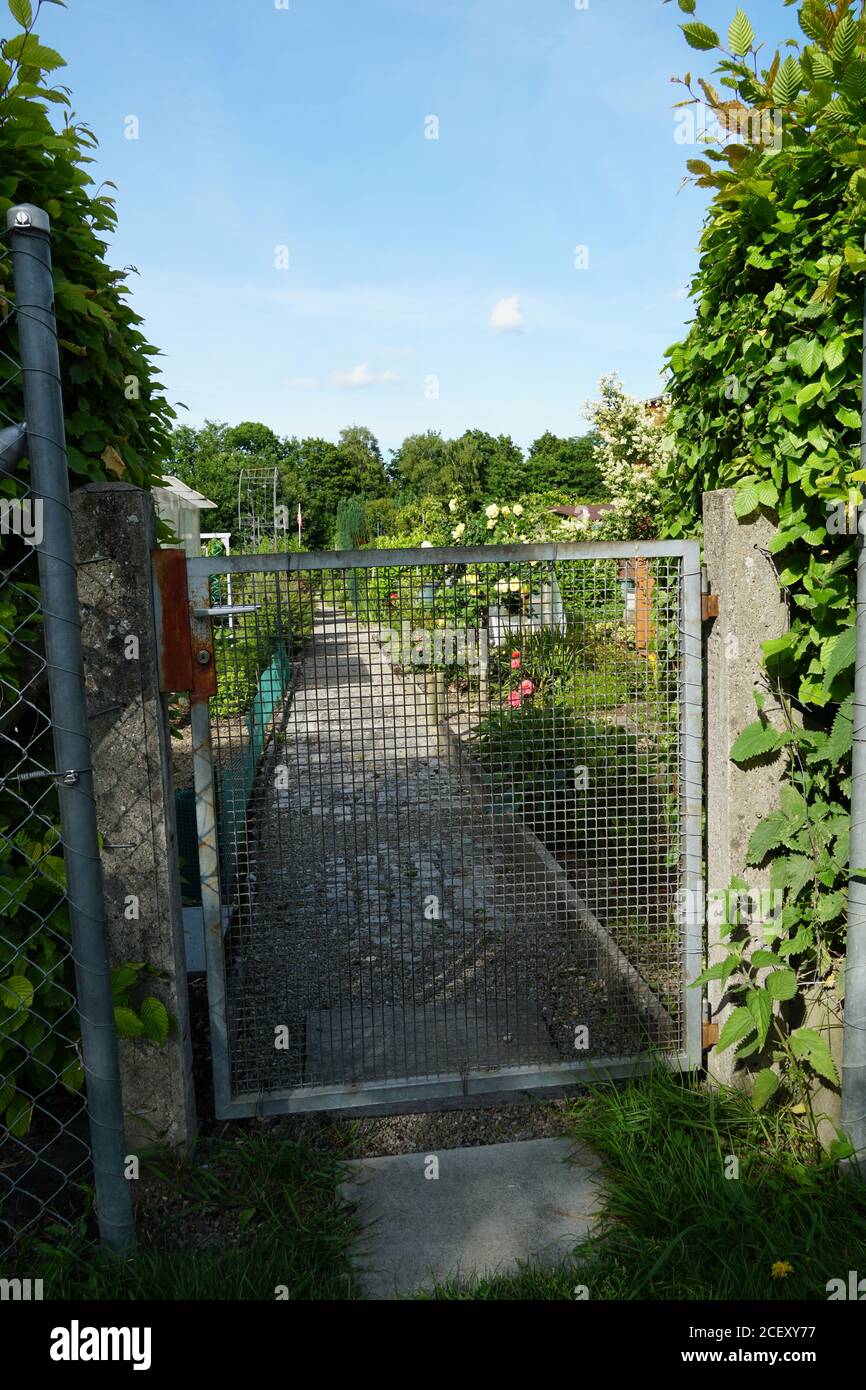 A metal meshed gate between two concrete pillars leading to an ...