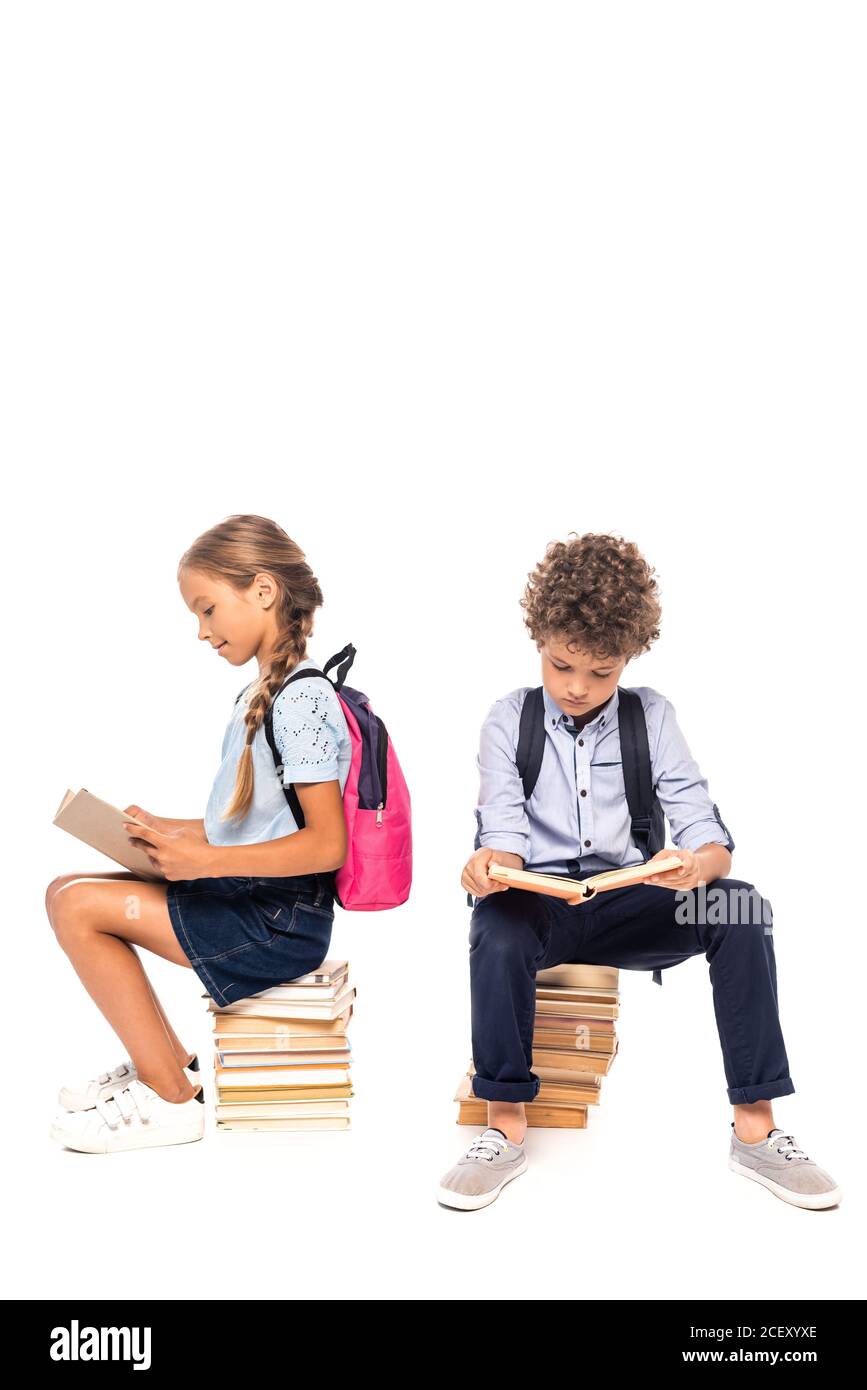 schoolkids sitting on books and reading isolated on white Stock Photo ...