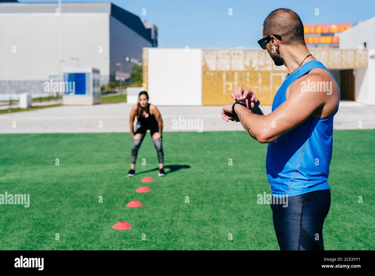 Side view of muscular male trainer noting time on wristwatch while ...