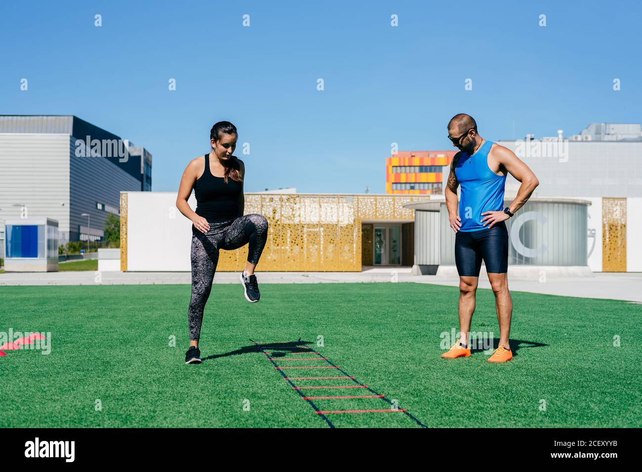 Full body young female athlete jumping on agility ladder during fitness ...