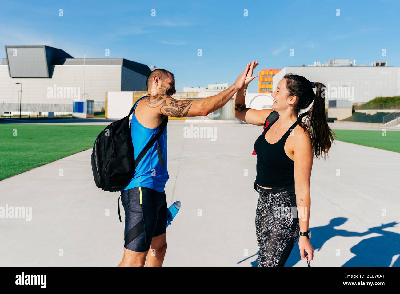 Side view of cheerful active athletes in sportswear giving high five ...
