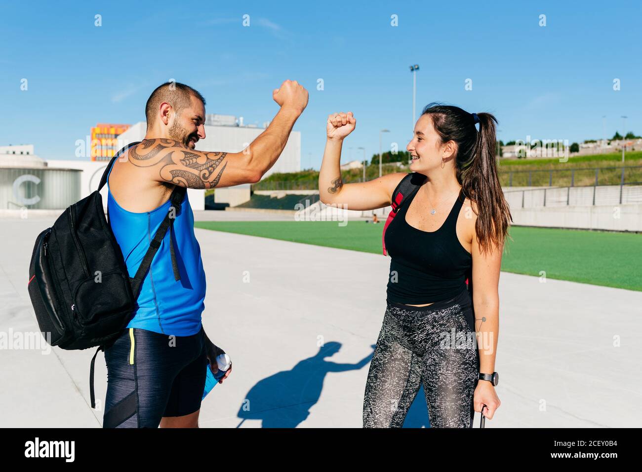 Side view of cheerful active athletes in sportswear giving high five ...