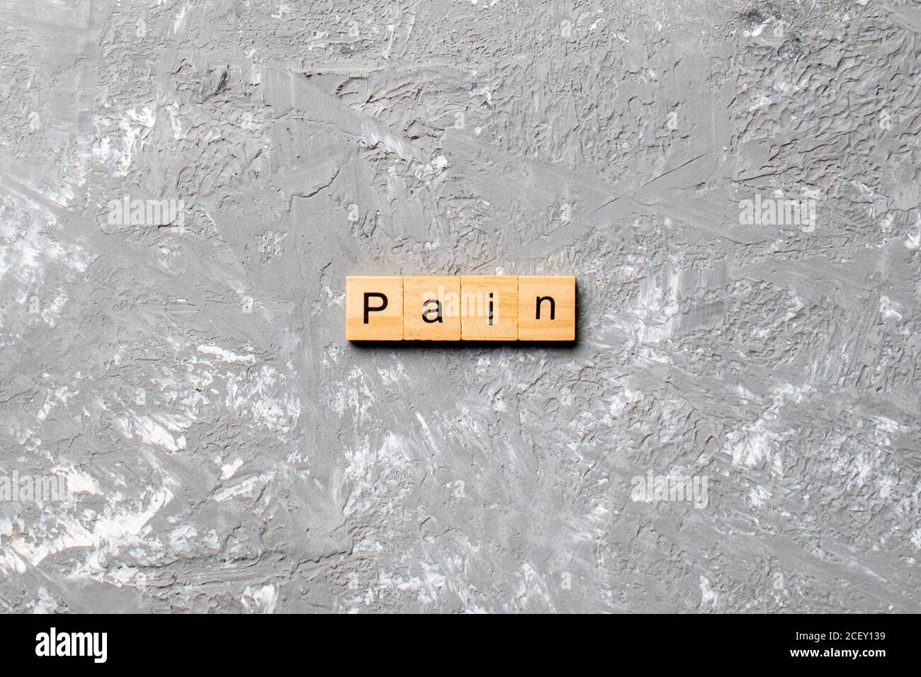 PAIN word written on wood block. PAIN text on cement table for your ...