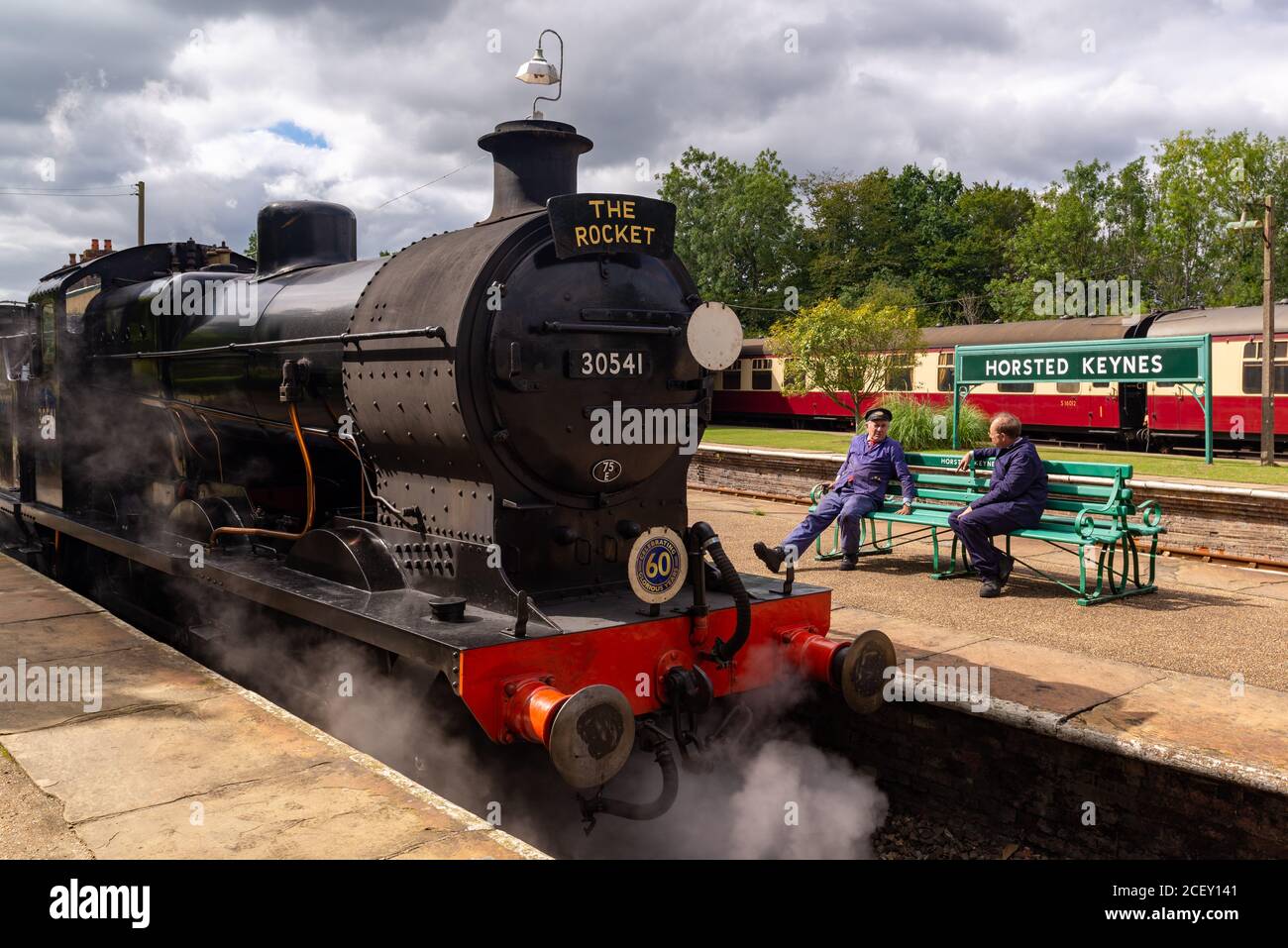 Staff in blue overalls beside The Rocket, black steam locomotive on the ...