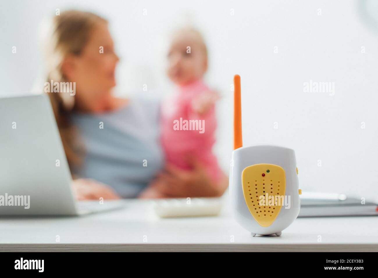Selective focus of baby monitor on table and woman holding kid at ...