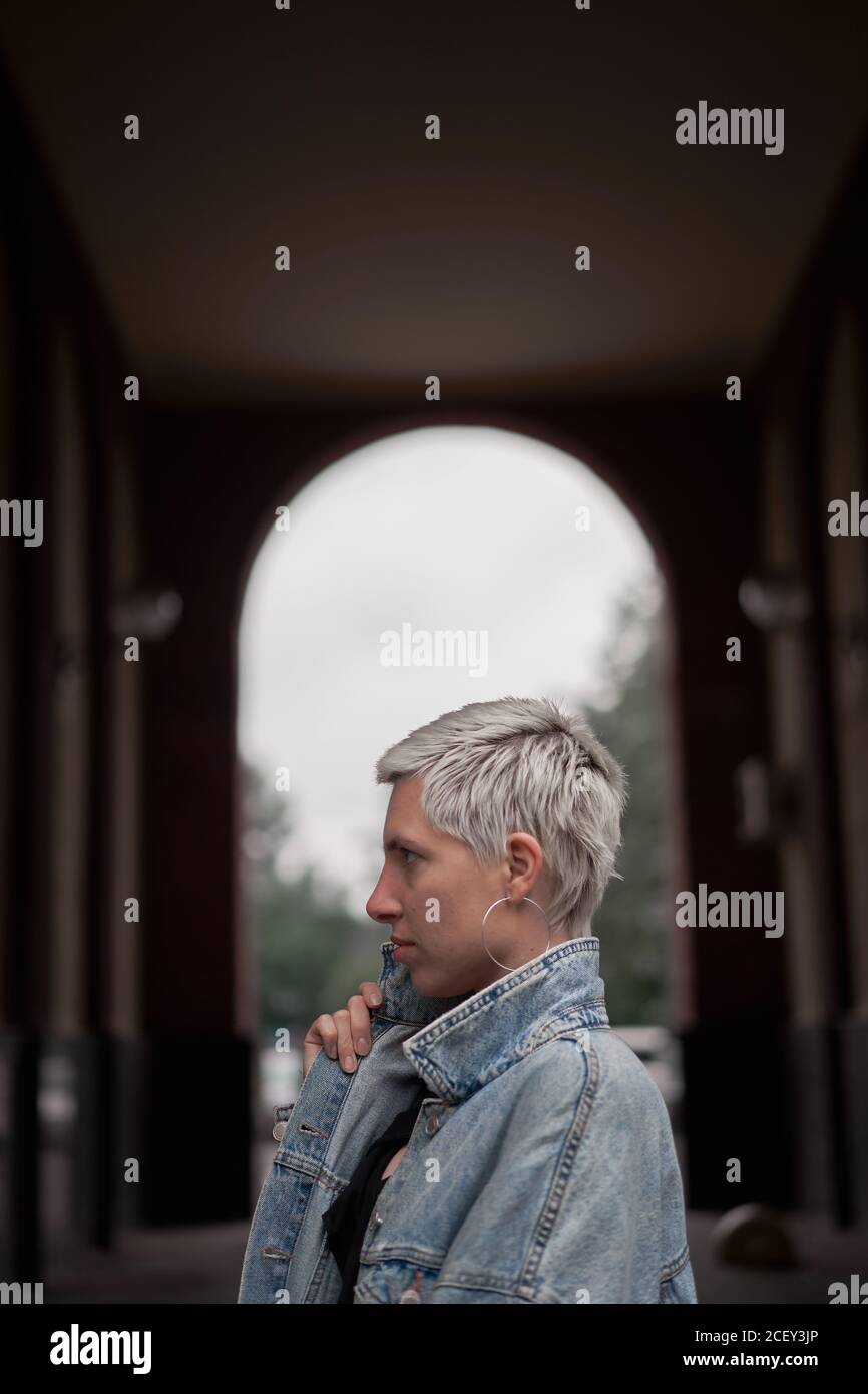 Side view of calm female model wearing denim jacket standing in arched ...