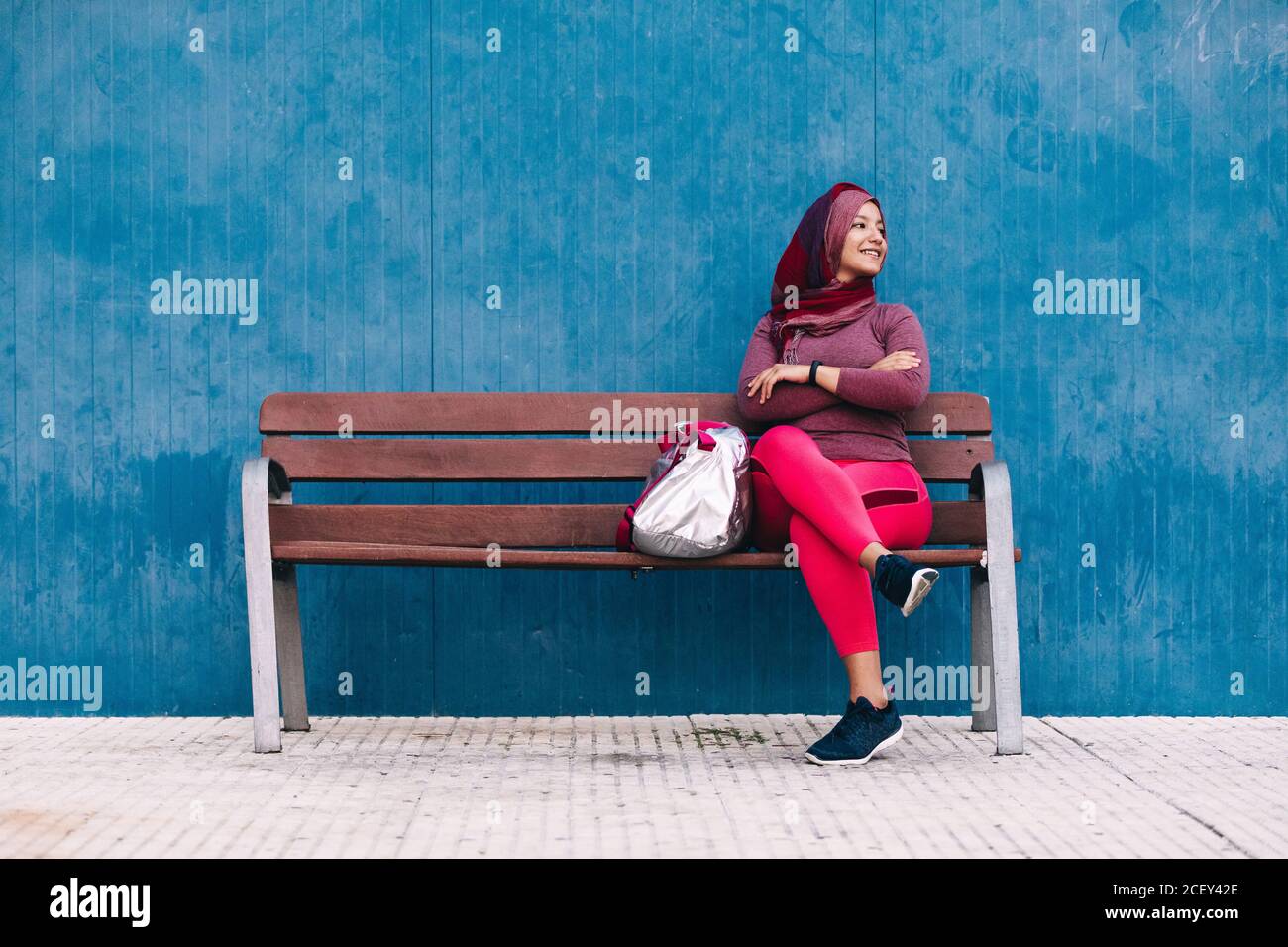 Content Arab female athlete in hijab sitting on a bench on the street ...