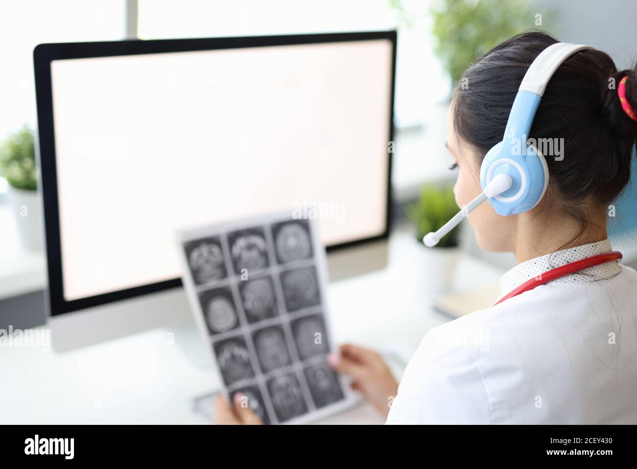 Woman doctor sits in medical office in headphones with microphone at ...
