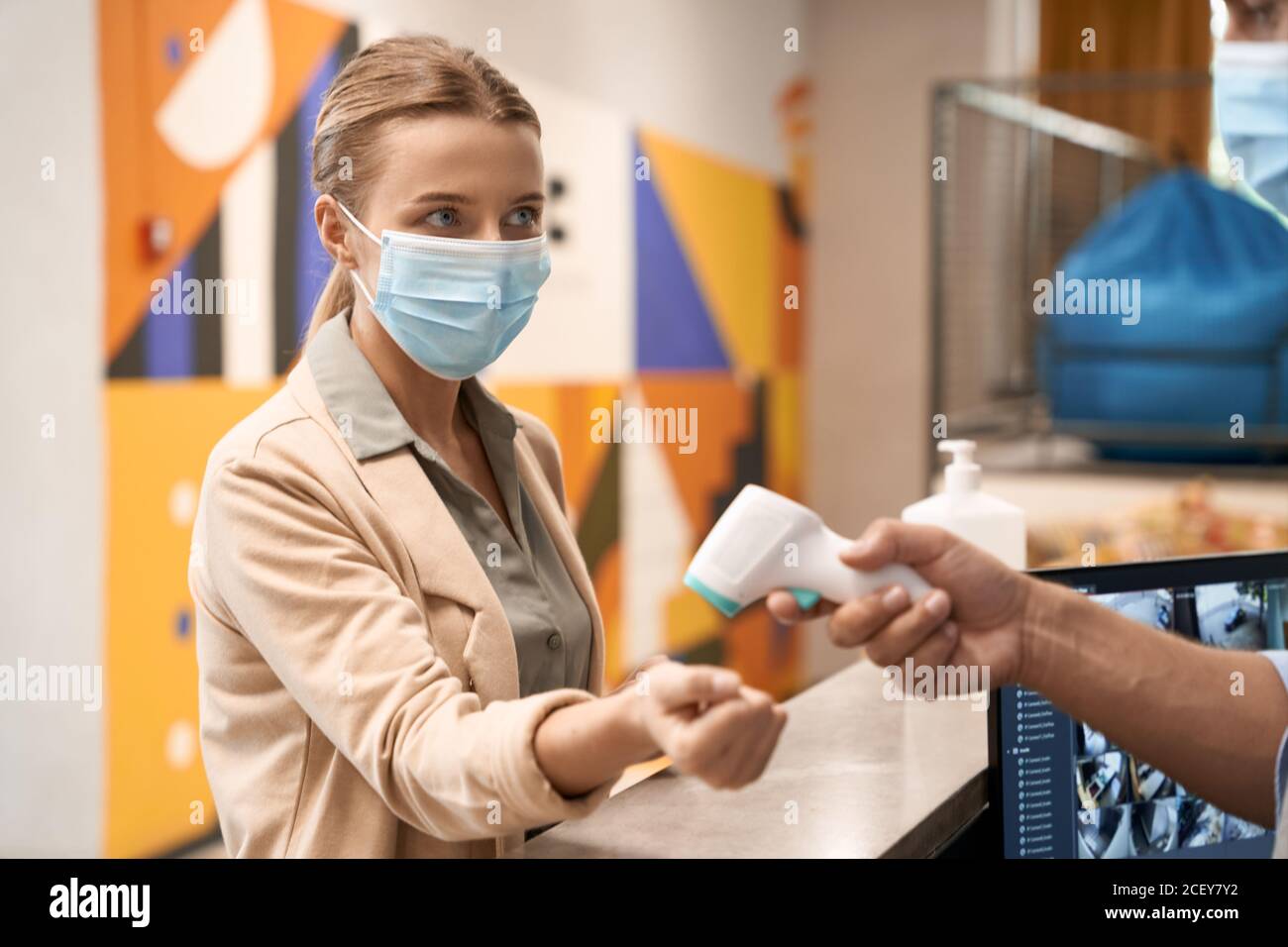 Male hand measuring body temperature of a young businesswoman wearing ...