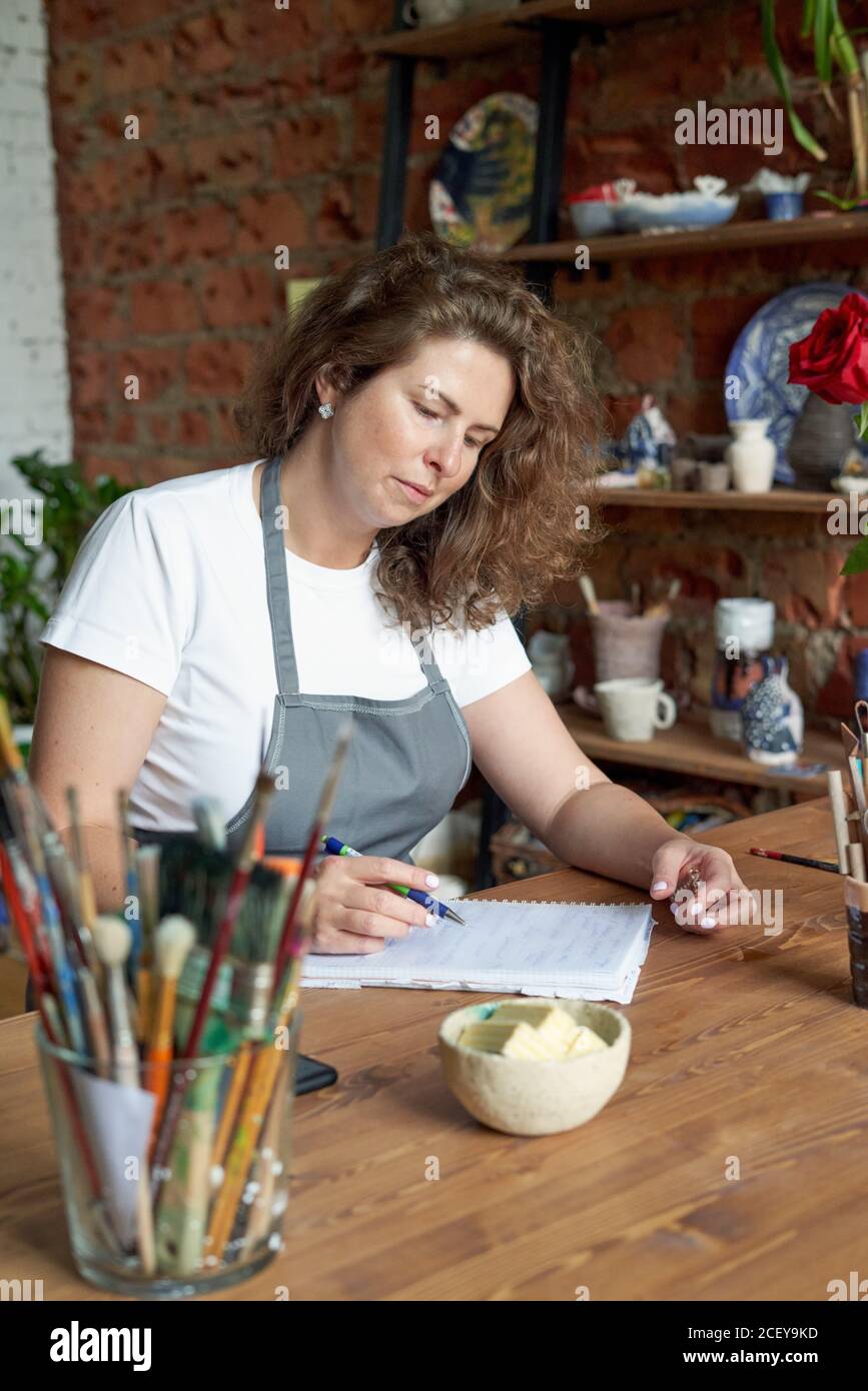 Artist woman writing in notebook, planning day in diary. Beautiful ...
