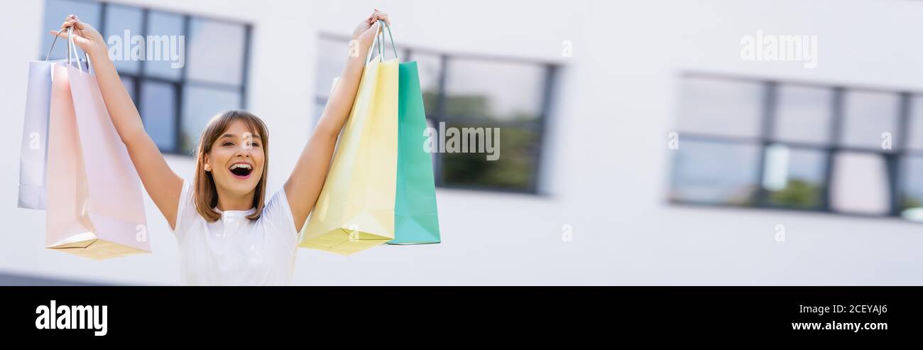 Horizontal crop of woman holding colorful shopping bags on urban street ...