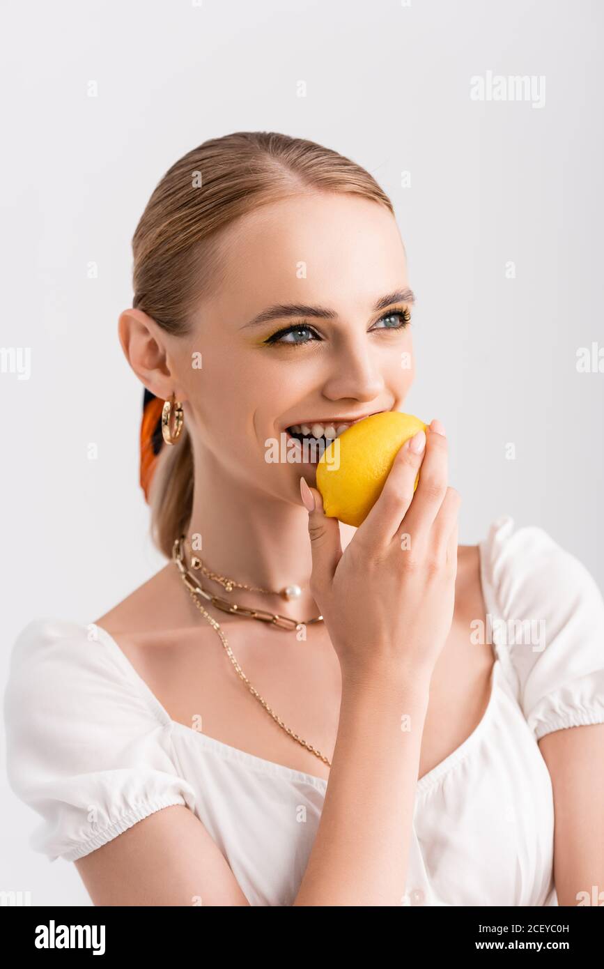 rustic blonde woman biting yellow lemon isolated on white Stock Photo ...