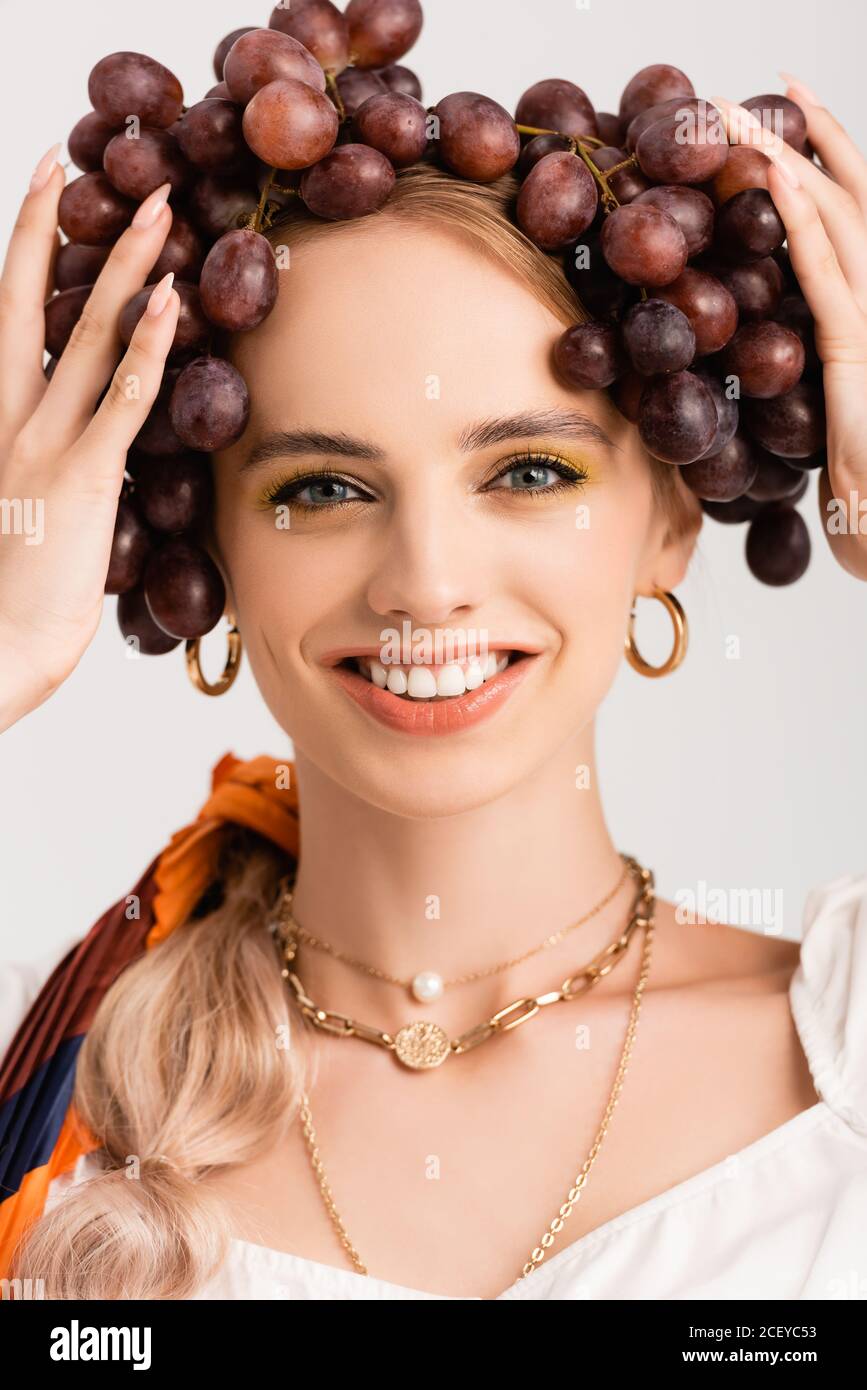 portrait of rustic blonde woman posing with grapes on head isolated on ...