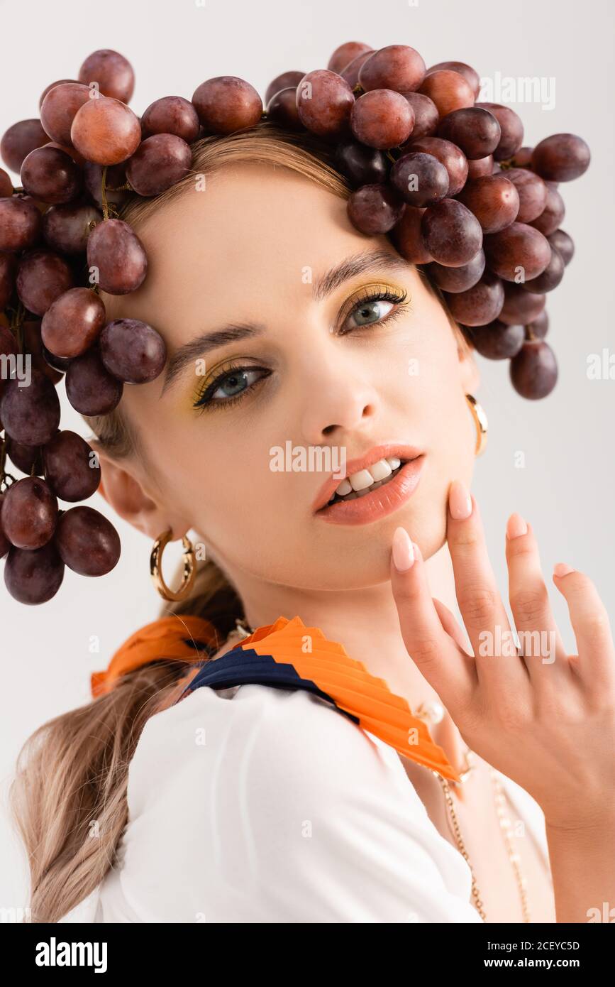 portrait of rustic blonde woman posing with grapes on head isolated on ...