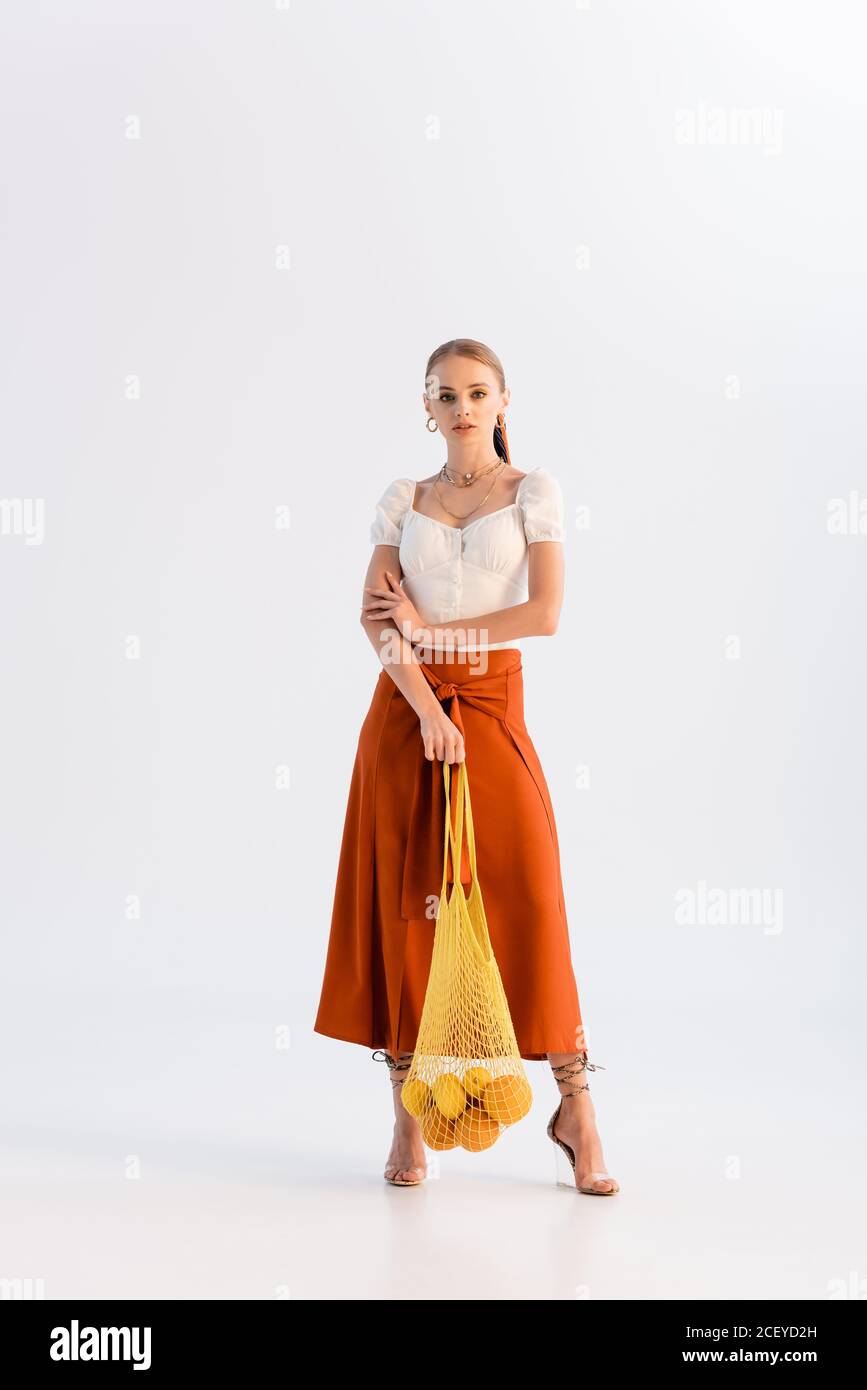full length view of fashionable woman posing with citrus fruits in ...
