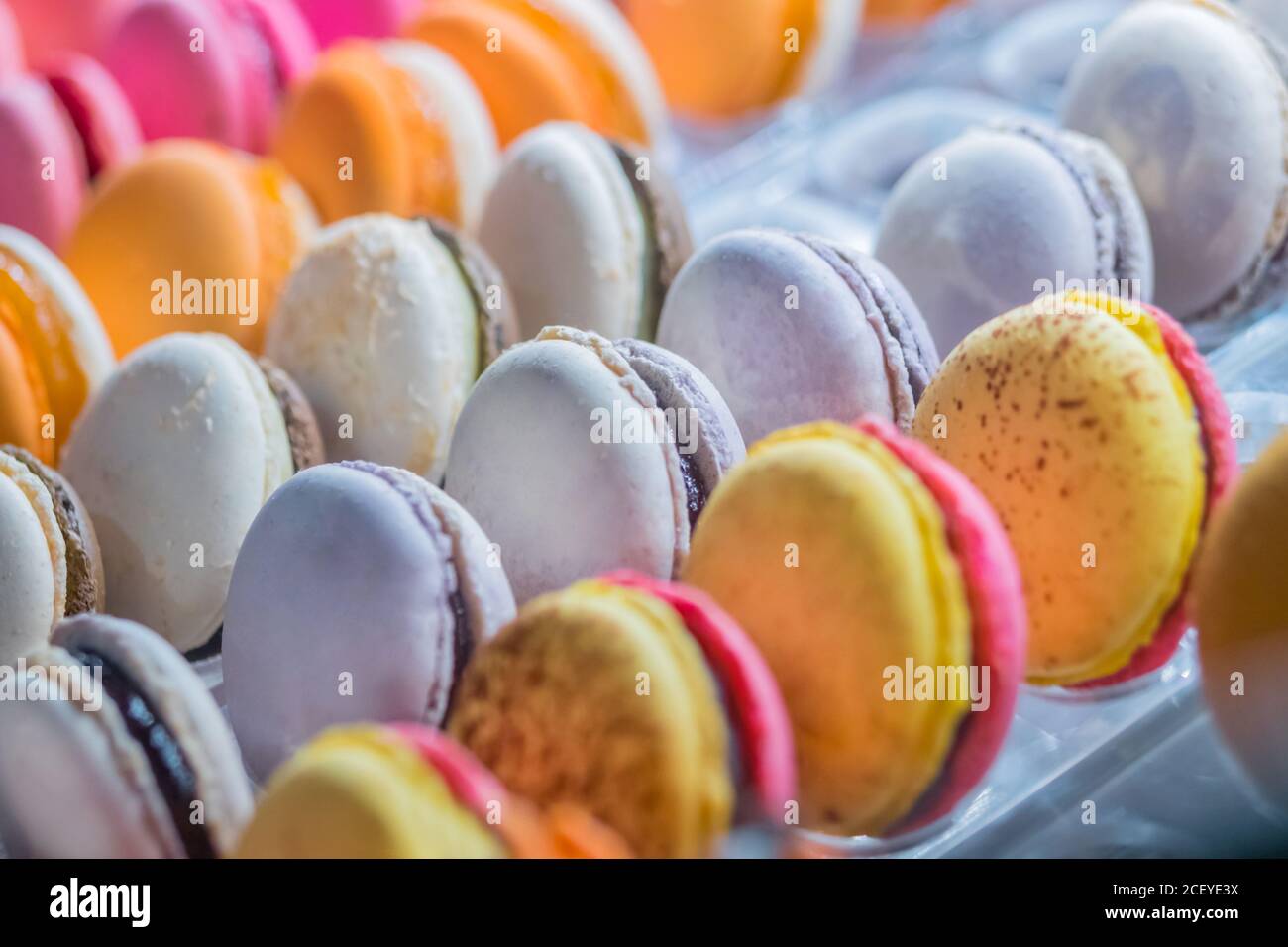 Rows of bright colorful macarons cakes for sale on counter of candy ...