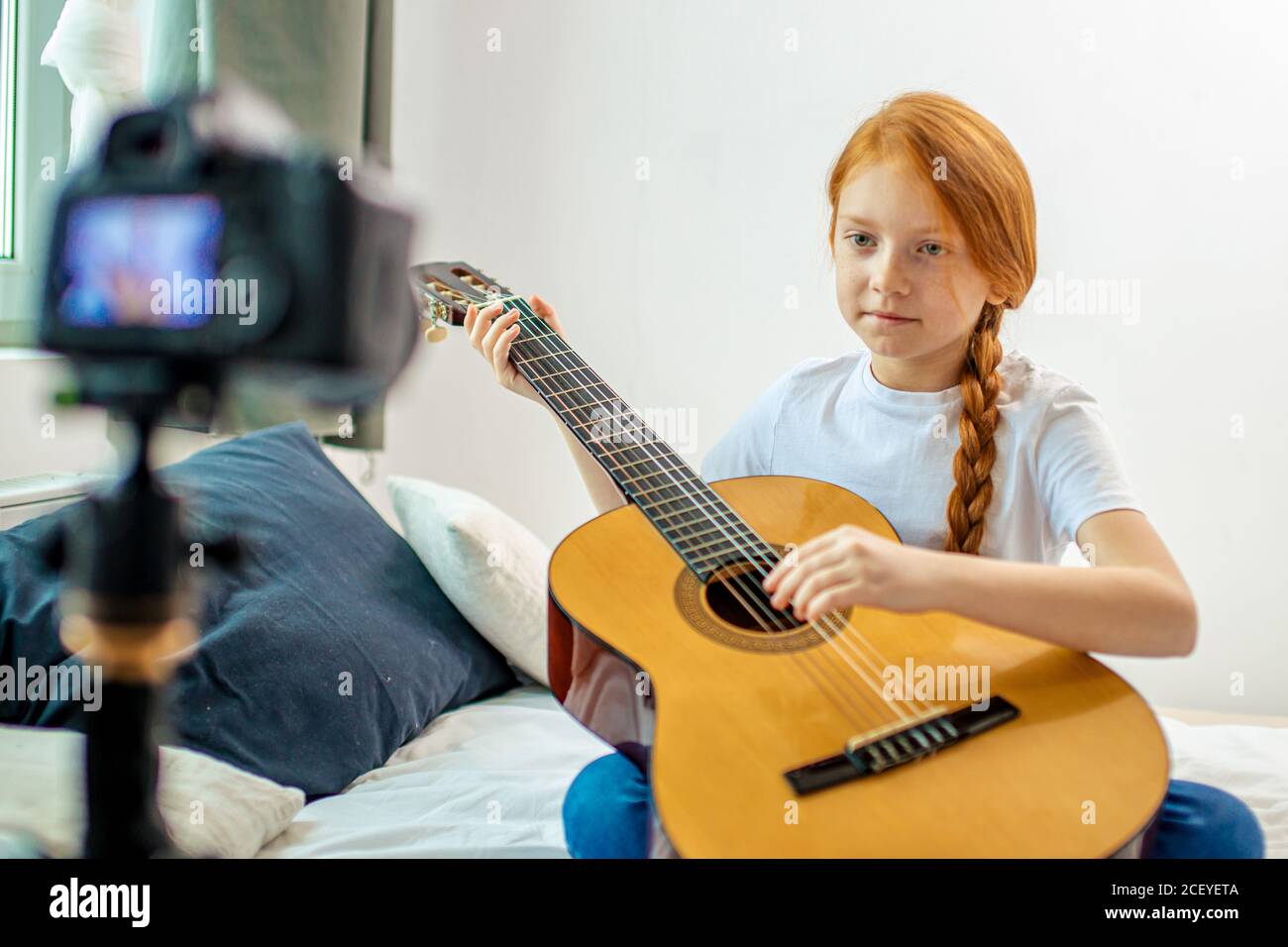 little caucasian blogger girl play guitar at camera. she performs music ...