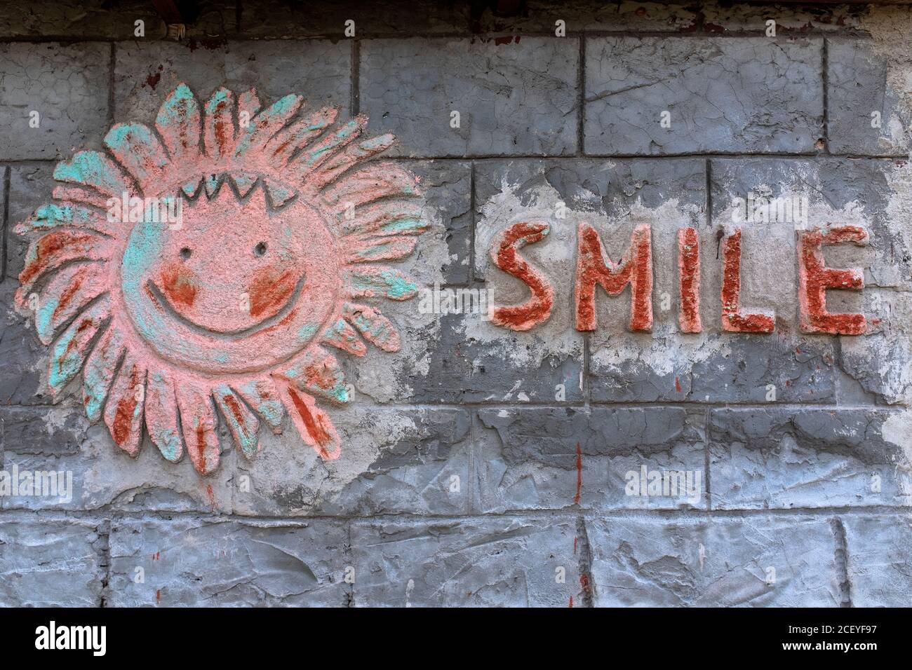 "smile" and sun face in cement on garage wall Stock Photo - Alamy
