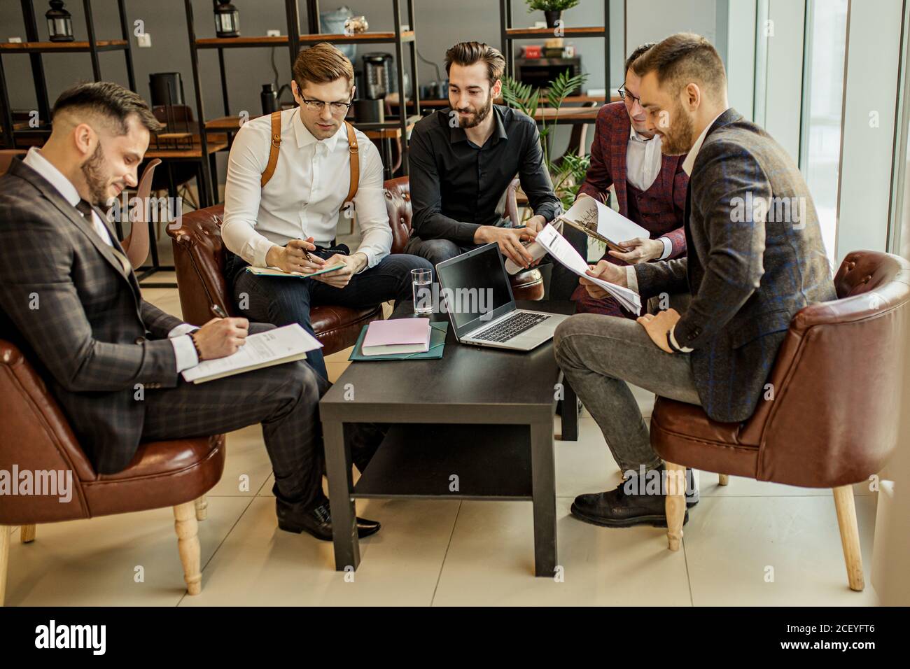 young caucasian business partners sharing and commenting reports ...