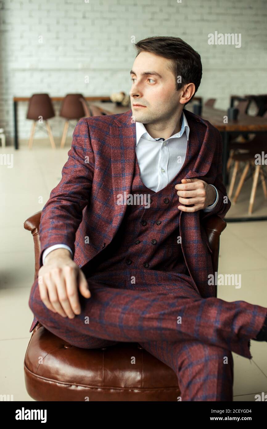 young caucasian personable man sit on leather chair in office, wearing ...