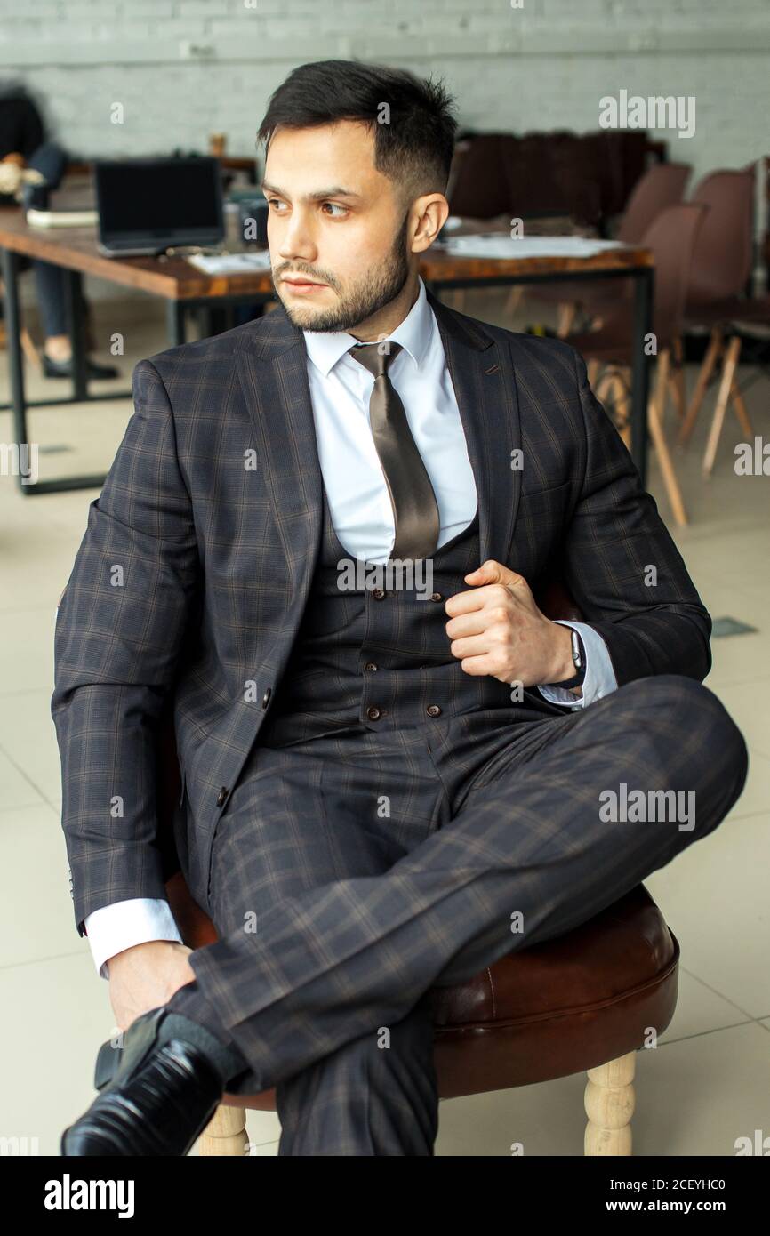 young business man sit on chair in office, wearing formal suit looks ...
