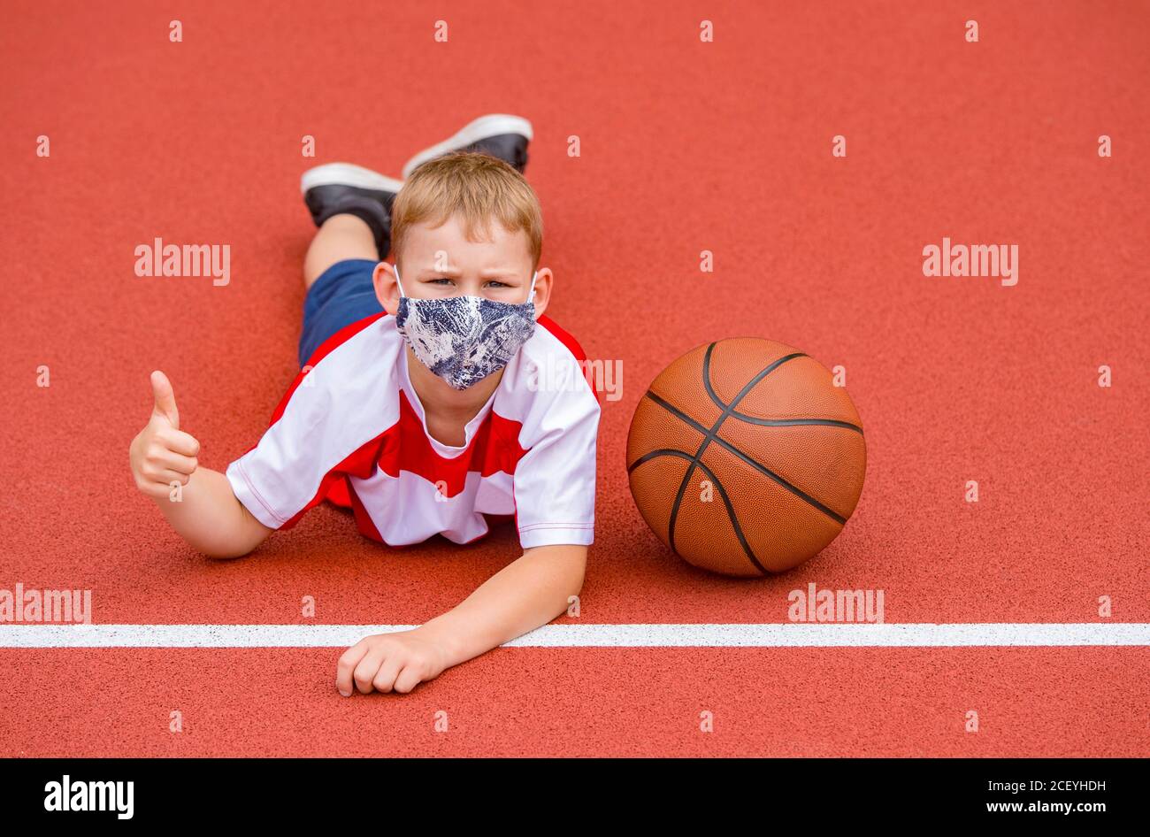 School kid with mask and basketball ball in a physical education lesson ...