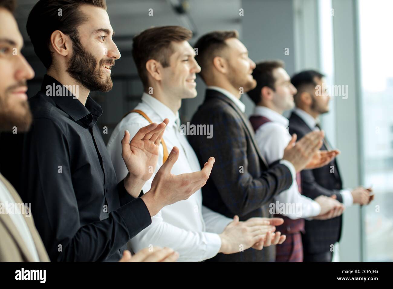 side view on happy group of young business men in suits celebrating ...