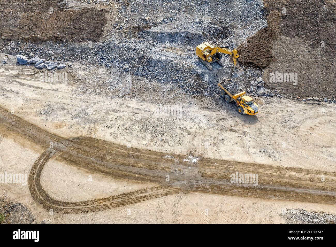 Drone photo - excavator loads heavy stones and debris on industrial ...