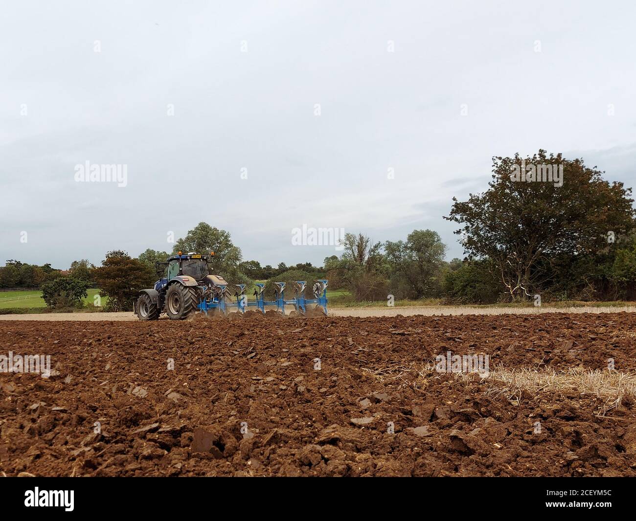 A farmer ploughing a field, tractor and plough Stock Photo - Alamy