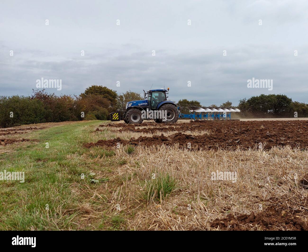 New Holland Tractor Ploughing Arable Farm Land, cloudy sky Stock Photo ...