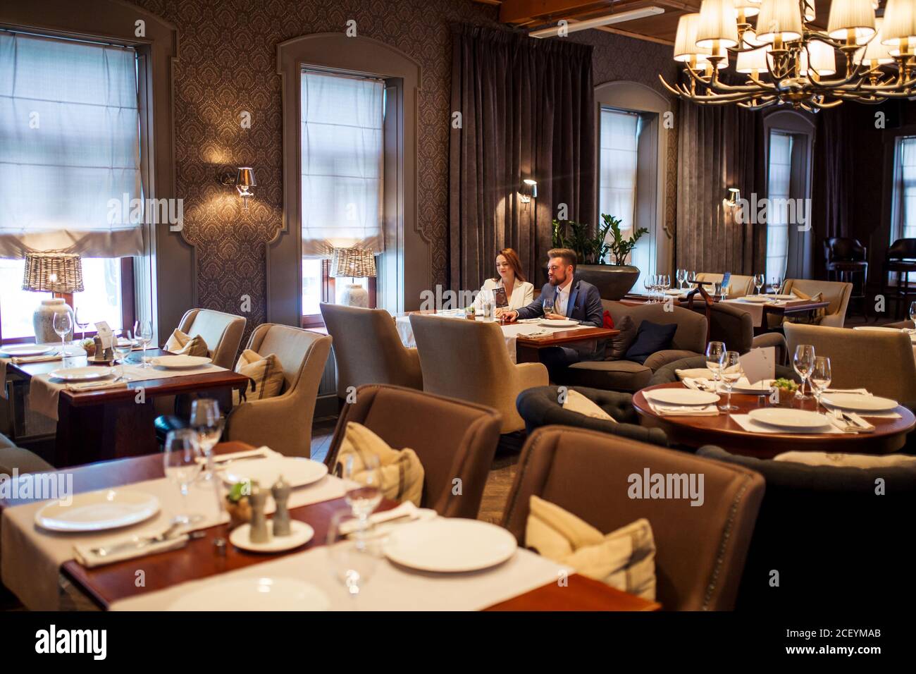 Young cheerful couple sitting in empty good lighted restaurant at ...