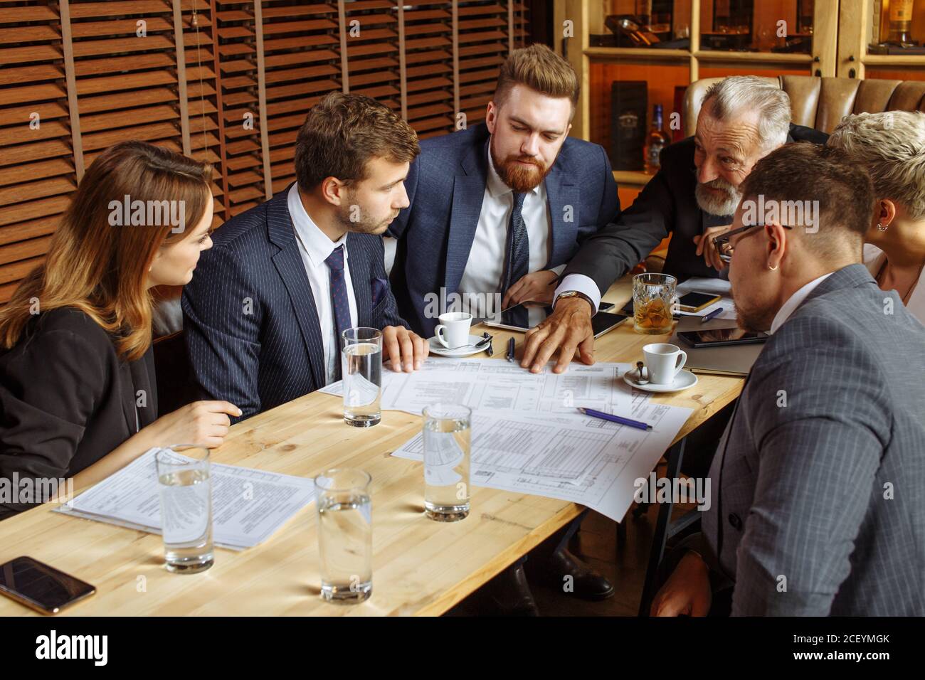 Good-natured gray-haired man in black suit leaning toward a young ...
