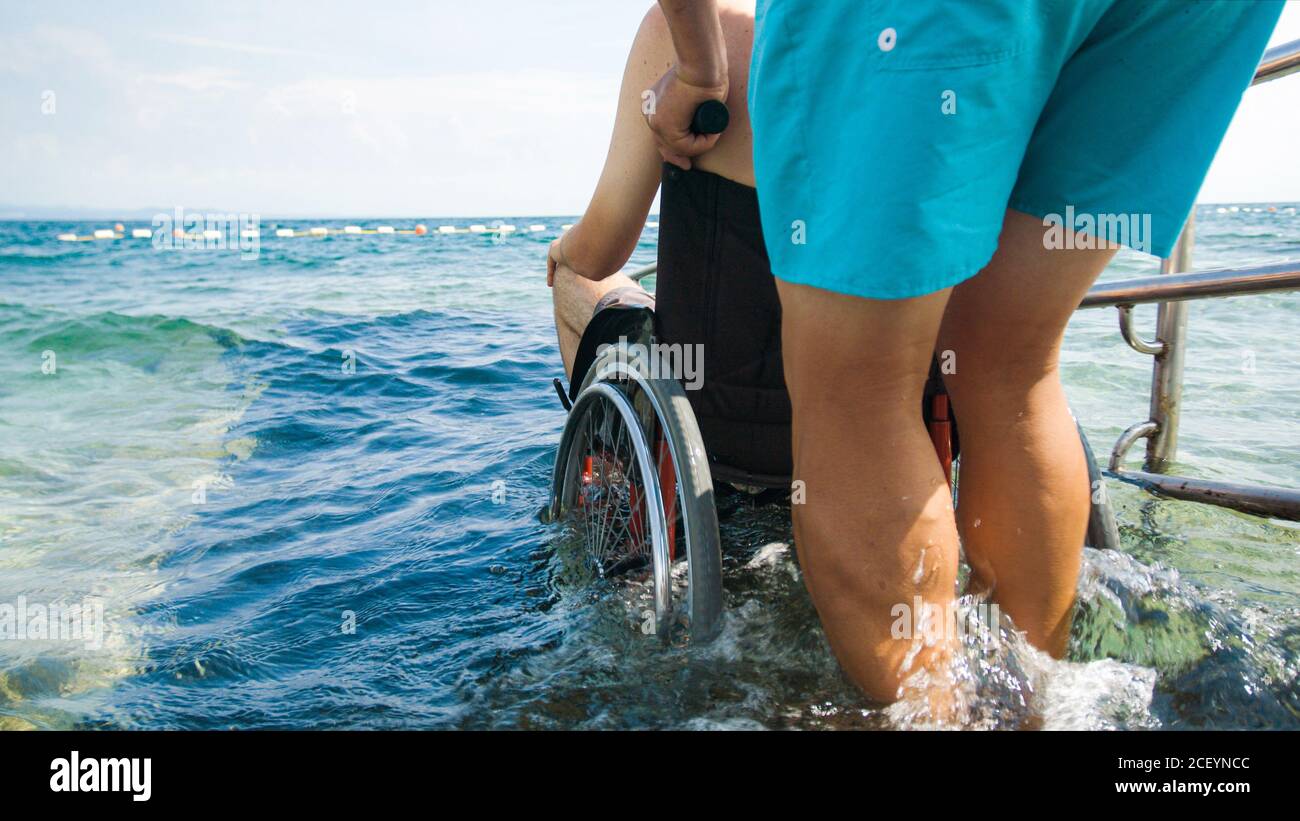 Disabled man at beach going for a swim with help of a wheelchair and ...