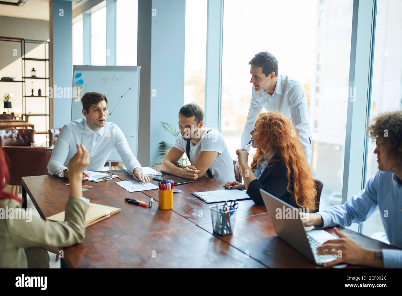 A team working on a business project actively. 6 people at the office ...